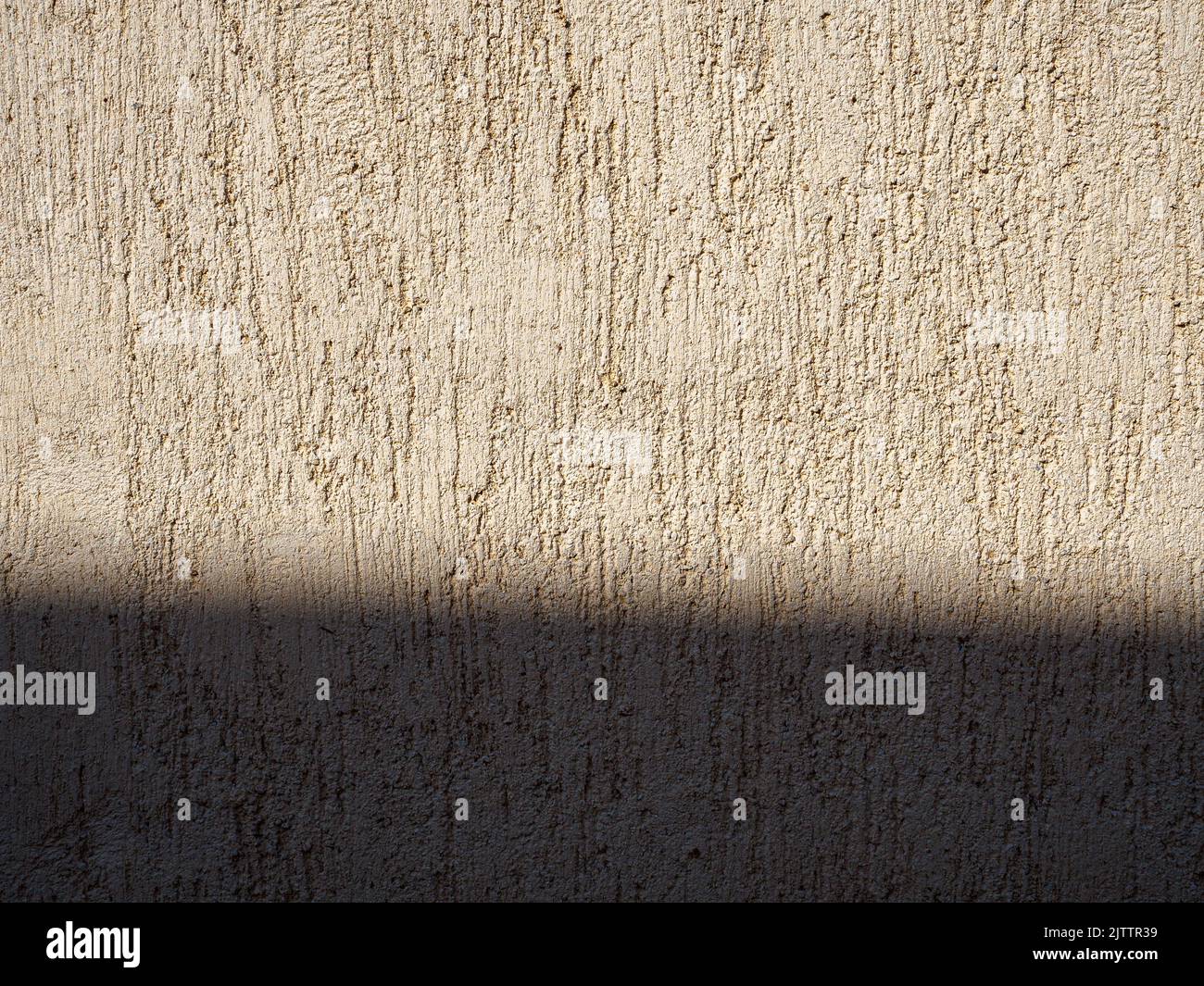 Beige textured wall with shadow and plaster applied with putty knife in ...