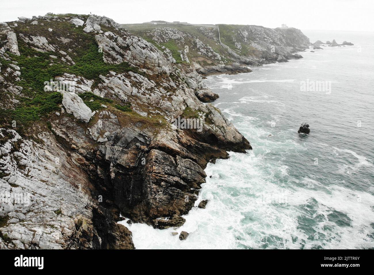 A Drone shot of a seascape with waves crashing huge rocks and a cliff ...