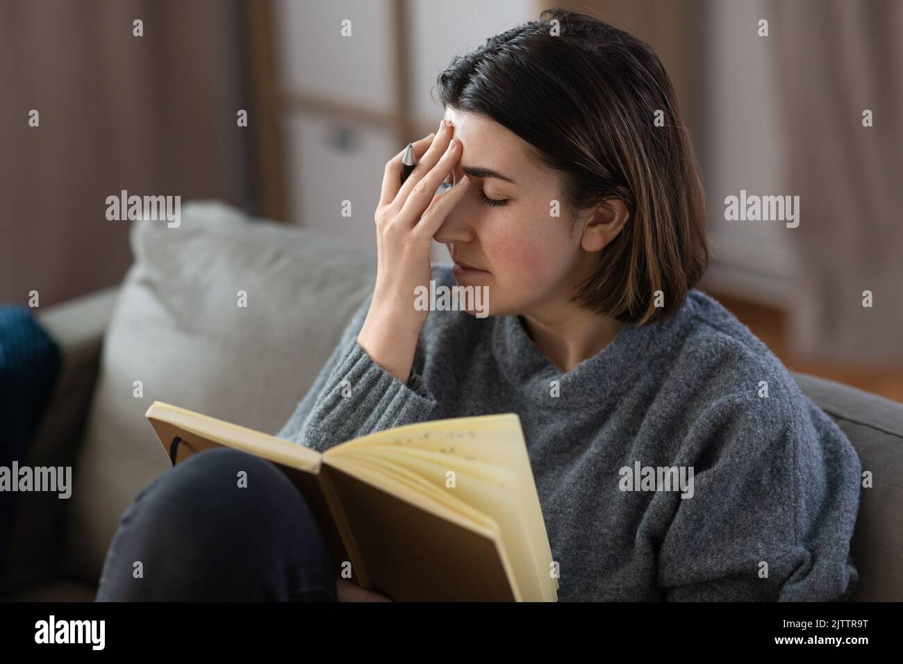 sad woman with diary sitting on sofa at home Stock Photo - Alamy