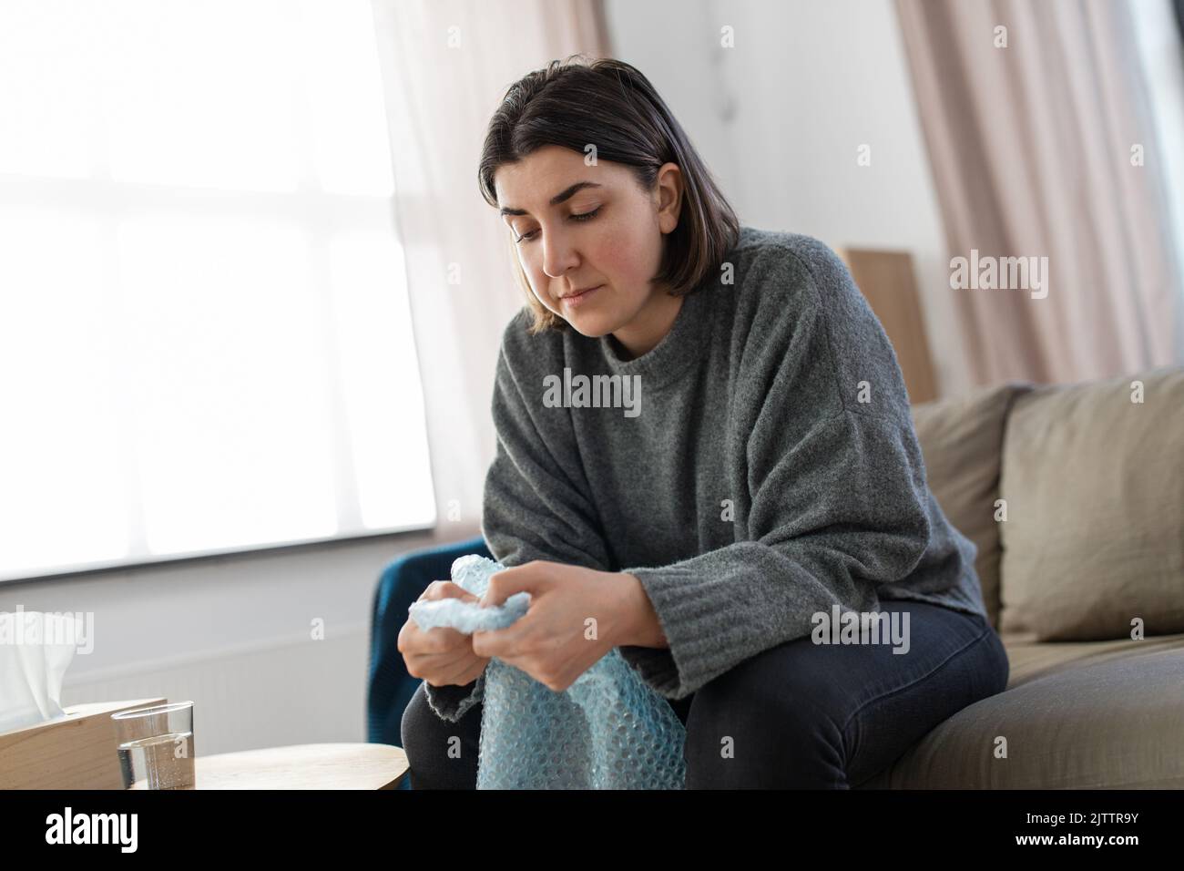 sad woman popping bubble wrap at home Stock Photo - Alamy