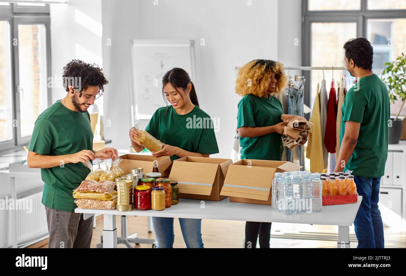 happy volunteers packing food and clothes in boxes Stock Photo - Alamy