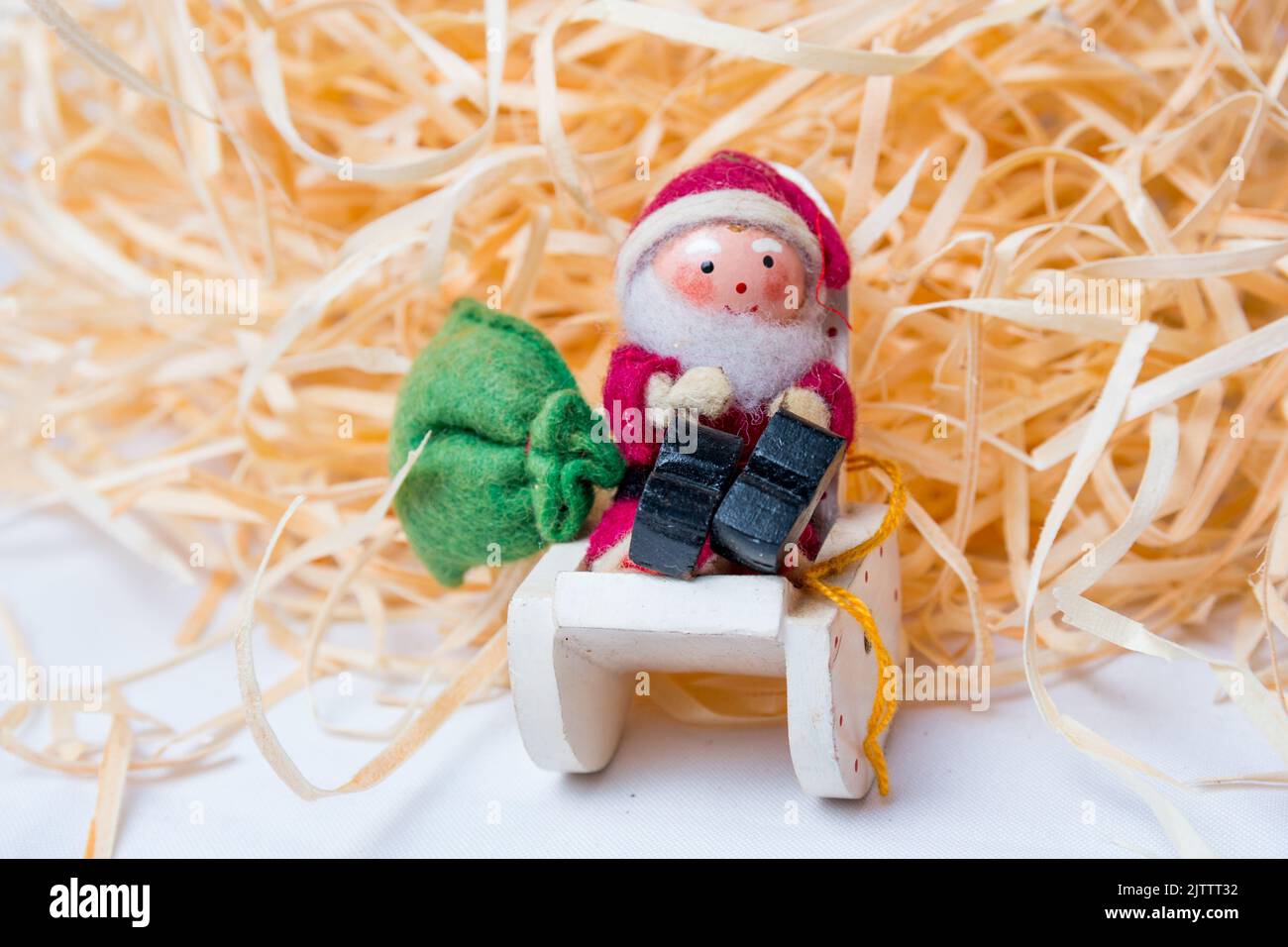 small wooden Santa Claus on a white background with straw in the ...