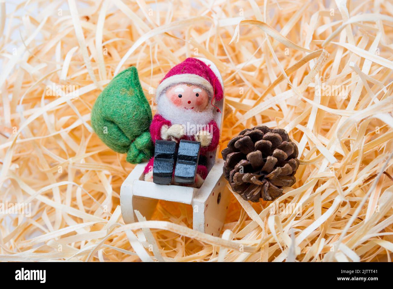 small wooden Santa Claus on a white background with straw in the ...