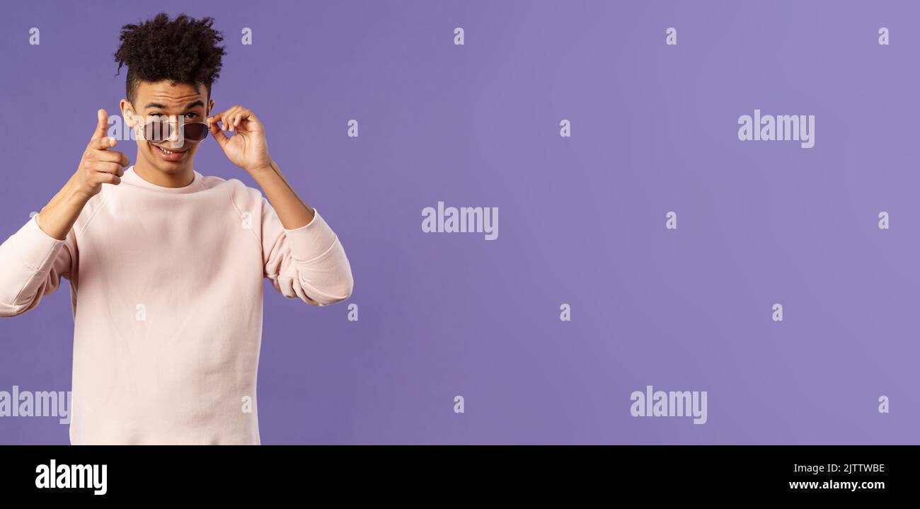 Portrait of cheeky handsome young man wearing sunglasses, take them off ...