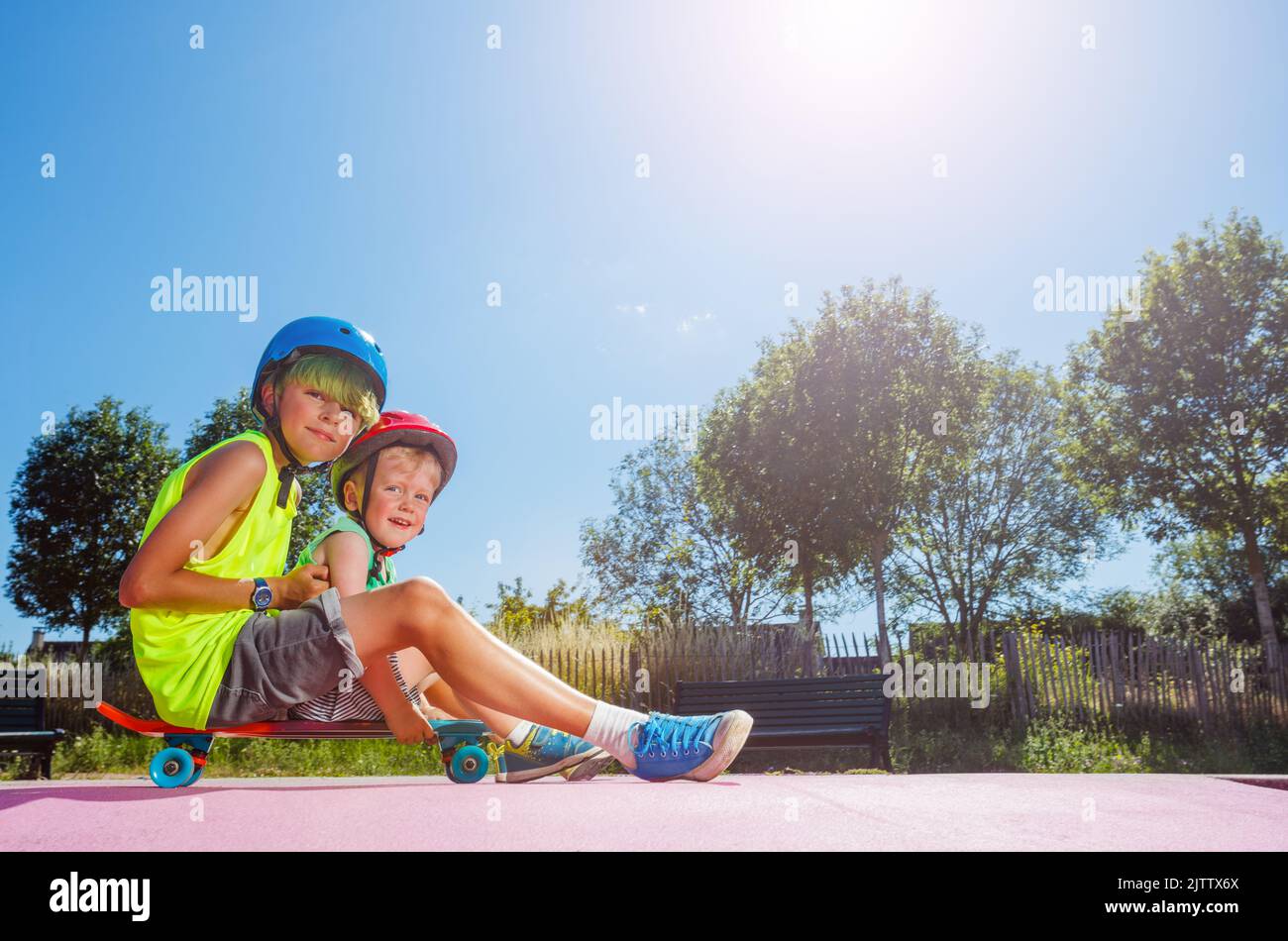 Two boys sit on the skate riding together in helmets Stock Photo - Alamy