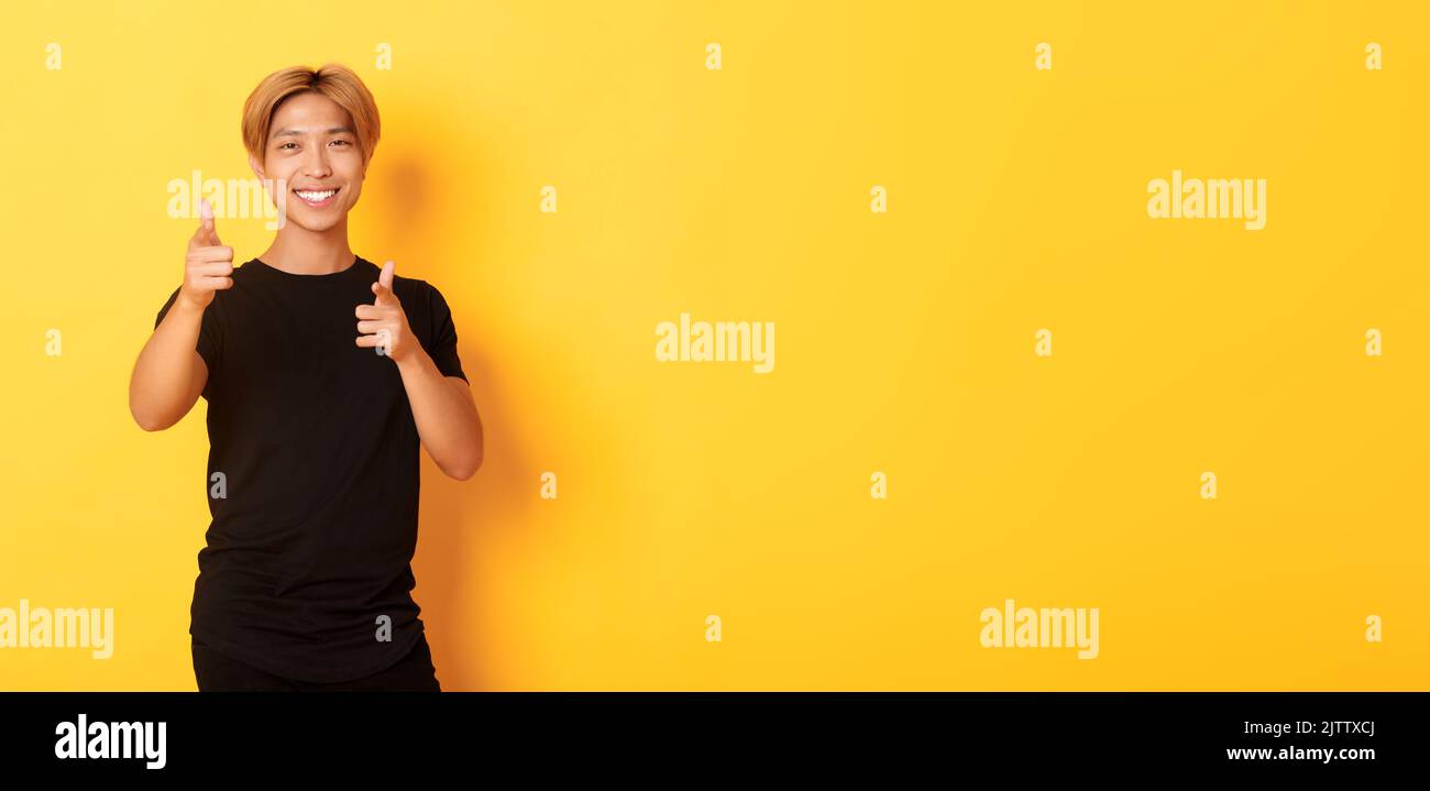 Portrait of cheeky smiling asian guy, looking satisfied and pointing ...