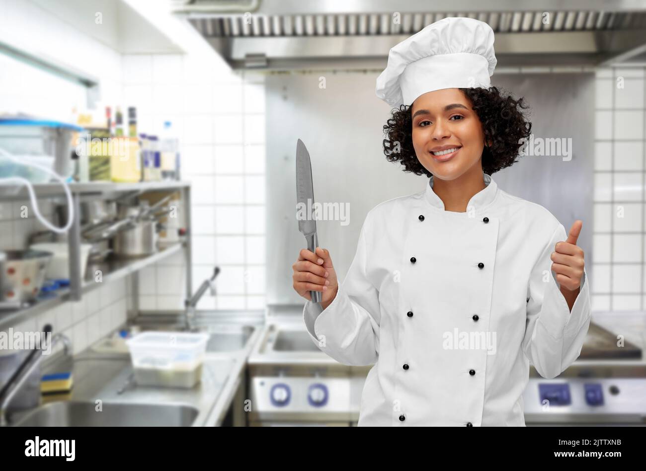 female chef in toque with knife showing thumbs up Stock Photo - Alamy