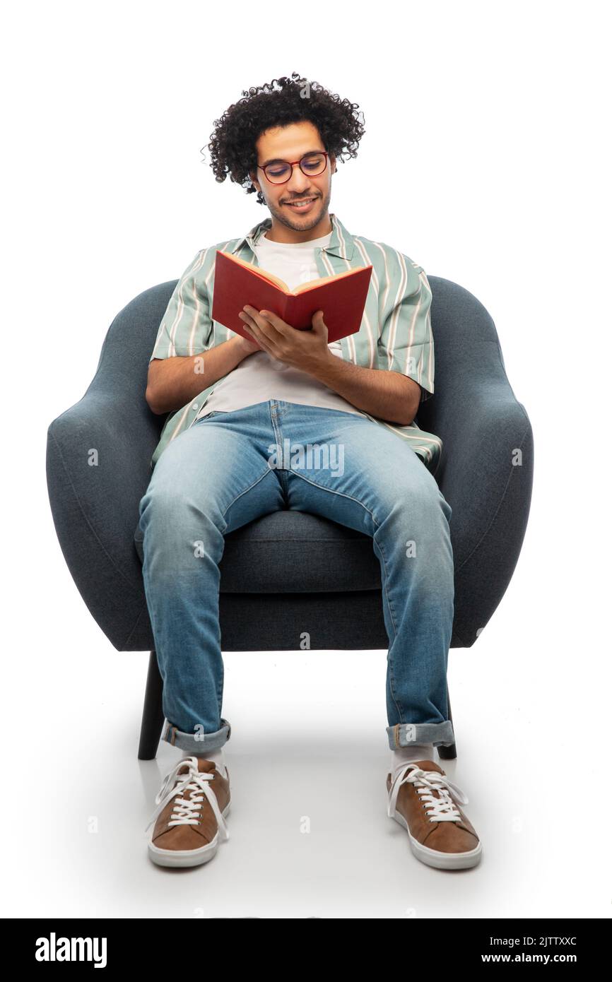 happy smiling man reading book sitting in chair Stock Photo - Alamy