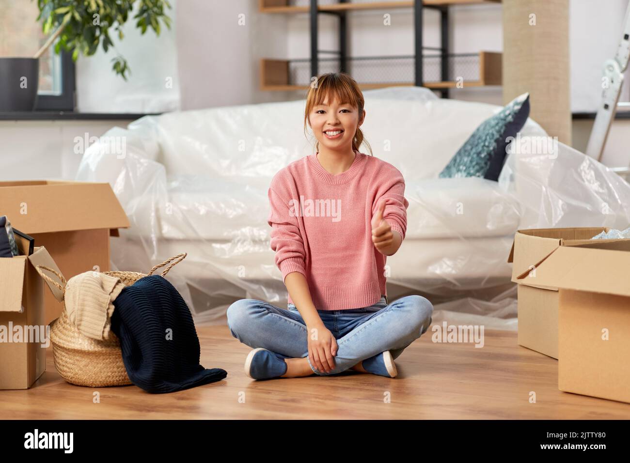 woman moving to new home and showing thumbs up Stock Photo - Alamy