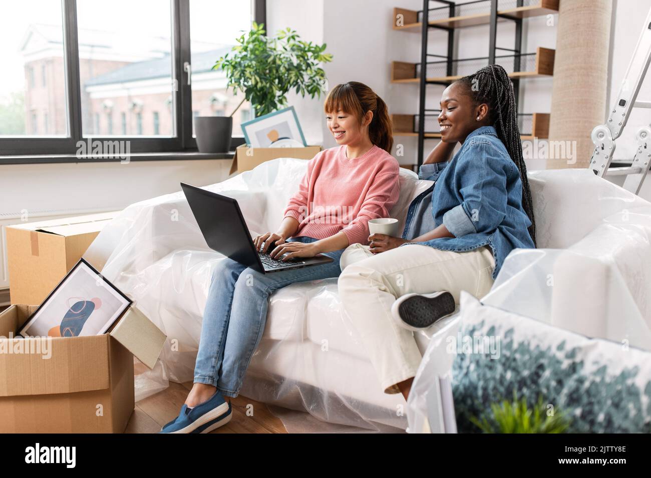 women using laptop and moving to new home Stock Photo - Alamy
