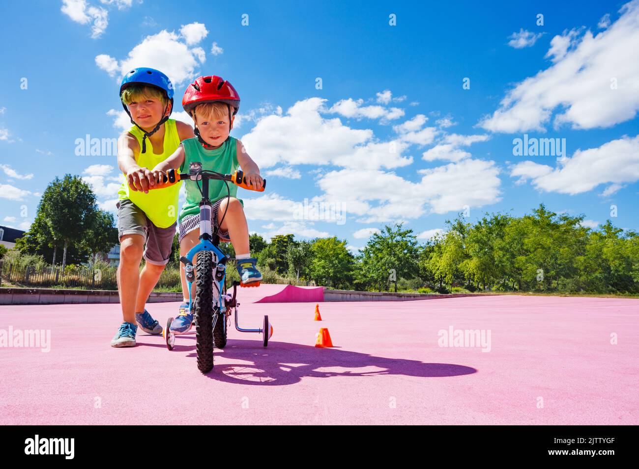 Boy help little brother to learn ride a bicycle pushing him Stock Photo ...