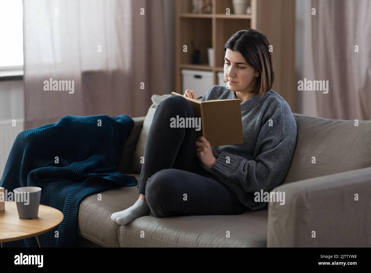 sad woman with diary sitting on sofa at home Stock Photo - Alamy