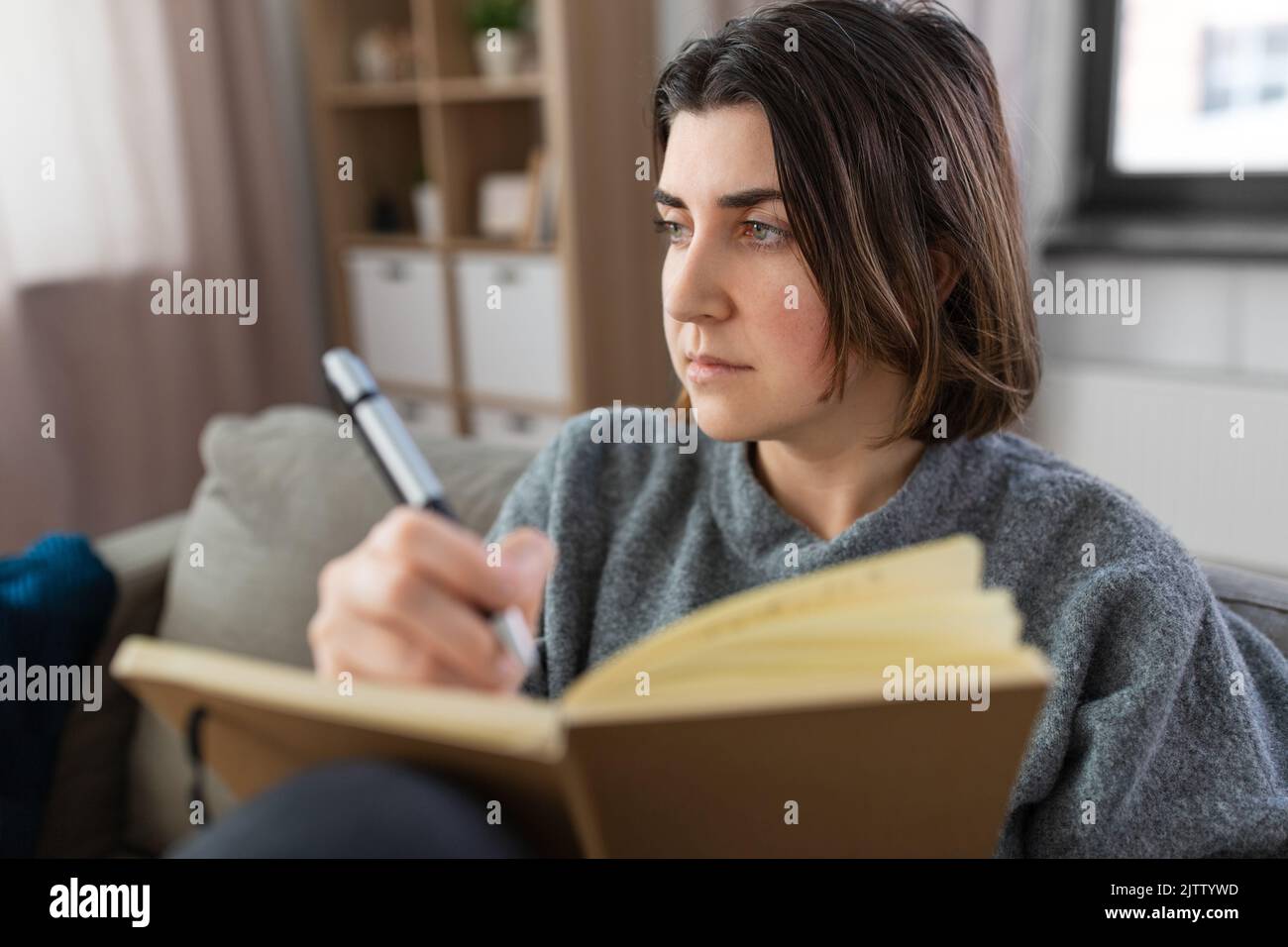 sad woman with diary sitting on sofa at home Stock Photo - Alamy