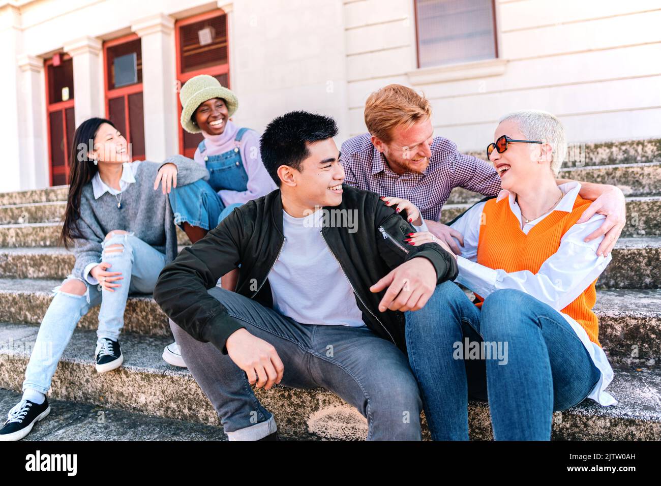 Group of multi-ethnic friends sitting talinkg and having fun together ...