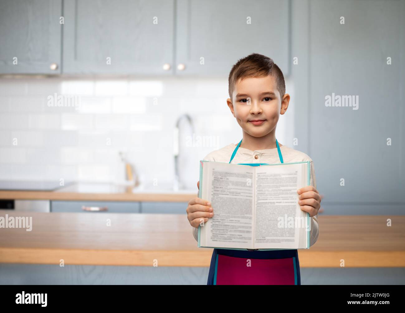 smiling little boy in apron reading cook book Stock Photo - Alamy