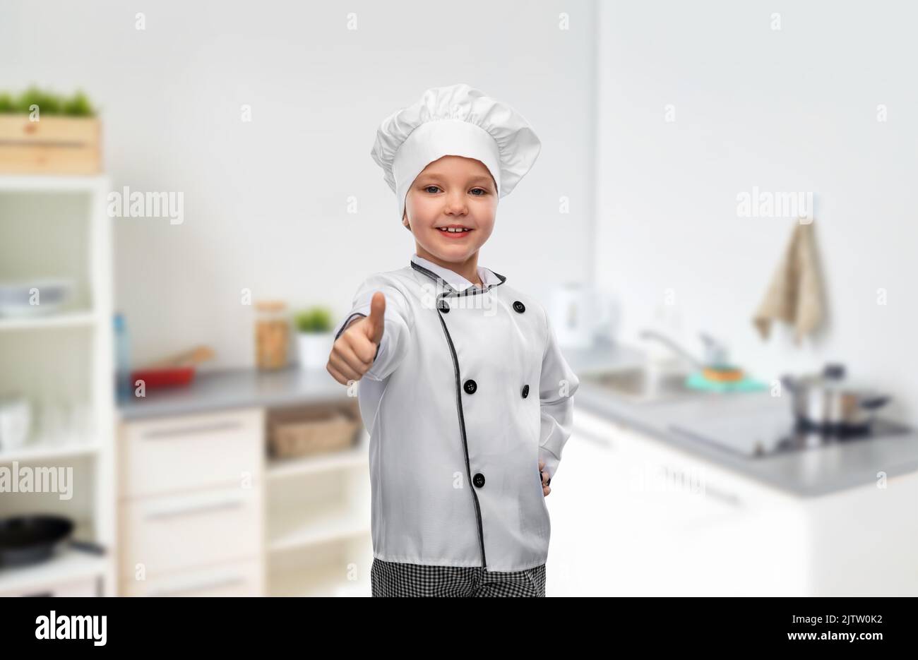girl in chef's toque showing thumbs up in kitchen Stock Photo - Alamy