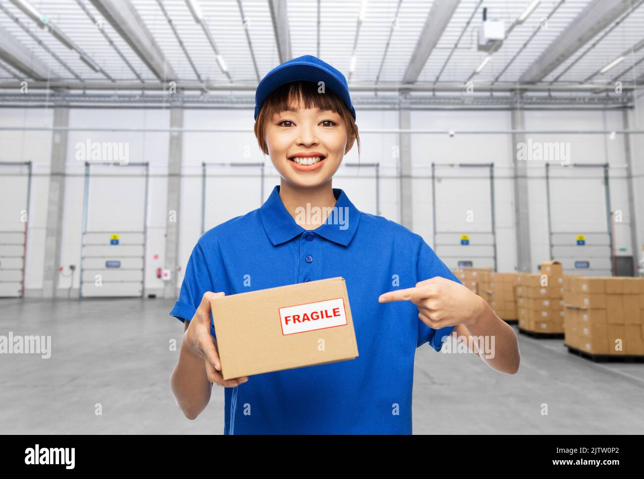 happy delivery woman with parcel at warehouse Stock Photo - Alamy