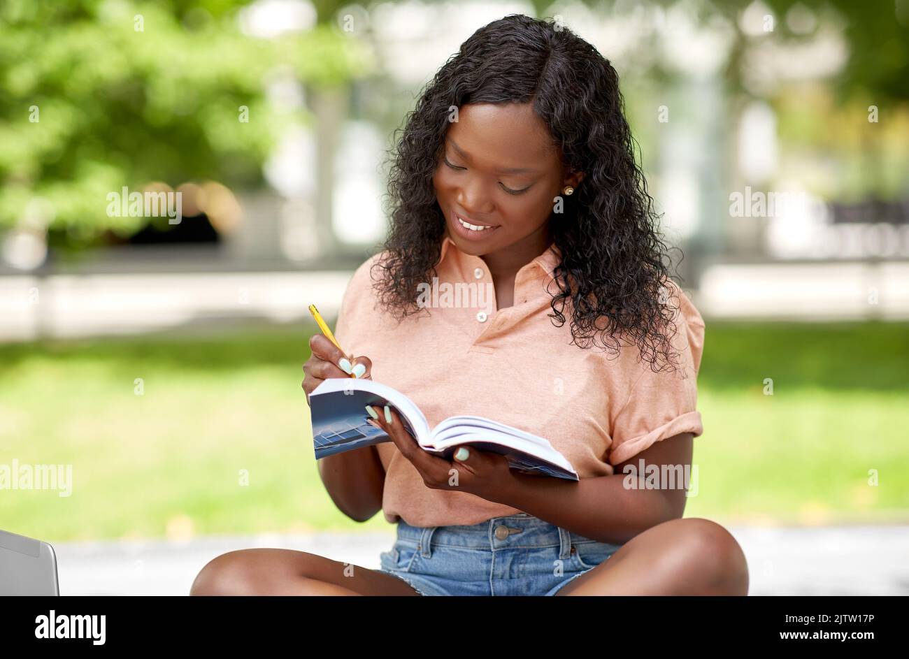 happy african student girl making notes in book Stock Photo - Alamy