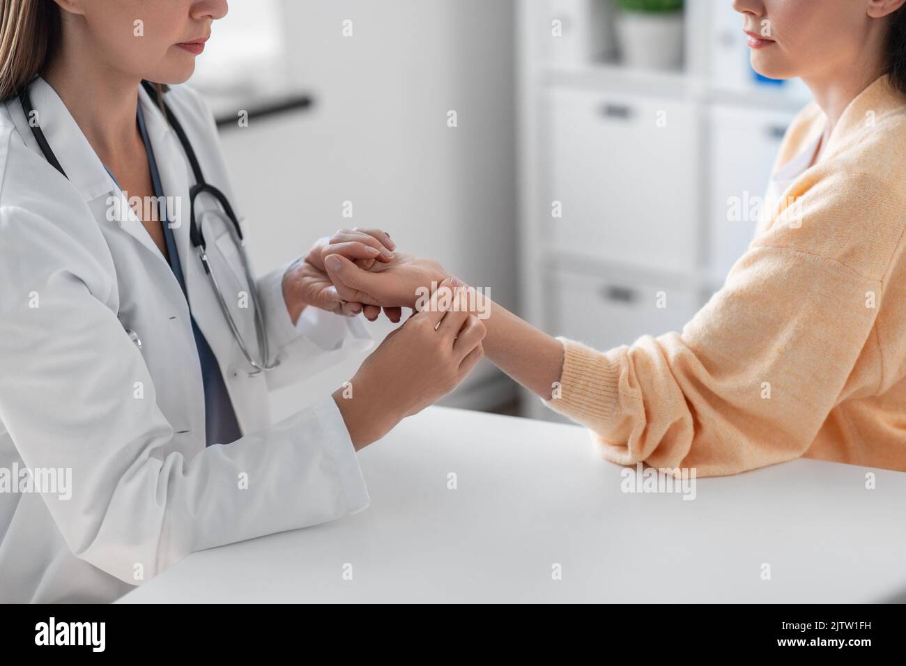 female doctor taking patient's pulse at clinic Stock Photo - Alamy
