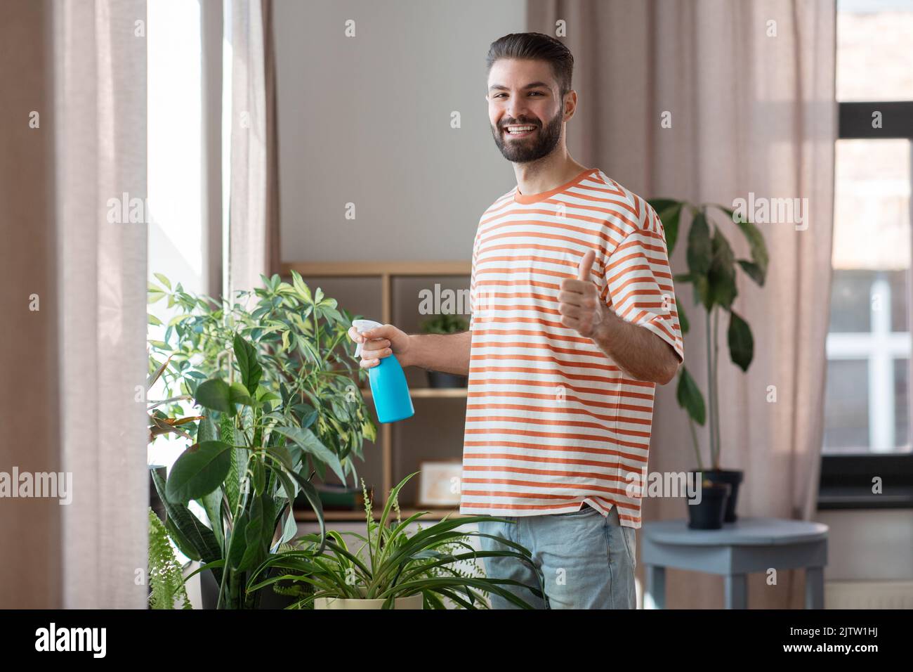 man spraying flowers and showing thumbs up at home Stock Photo - Alamy