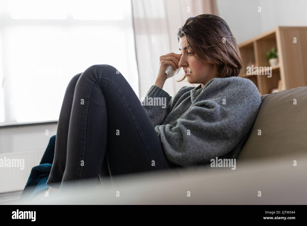 crying woman with tissue sitting on sofa at home Stock Photo - Alamy