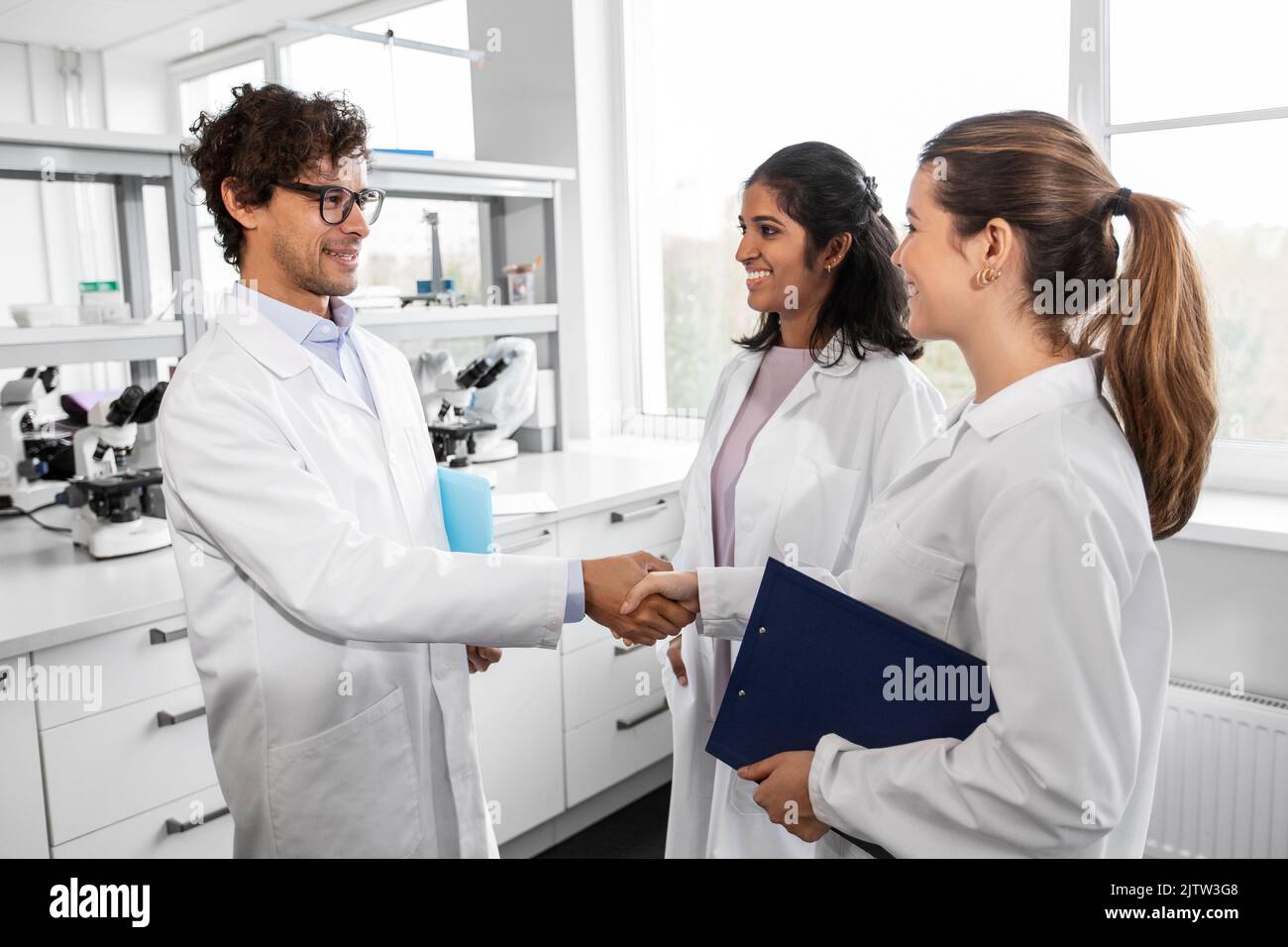 scientists shaking hands in laboratory Stock Photo - Alamy