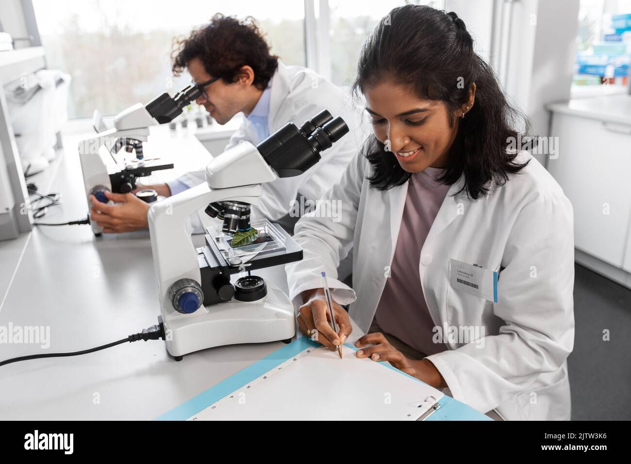 scientists with microscopes working in laboratory Stock Photo - Alamy