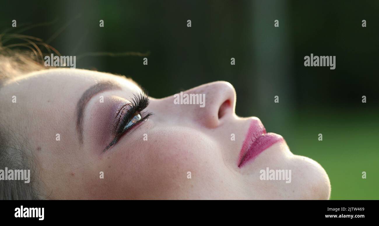 Pretty girl face looking at the sky with faith, feeling the presence of ...