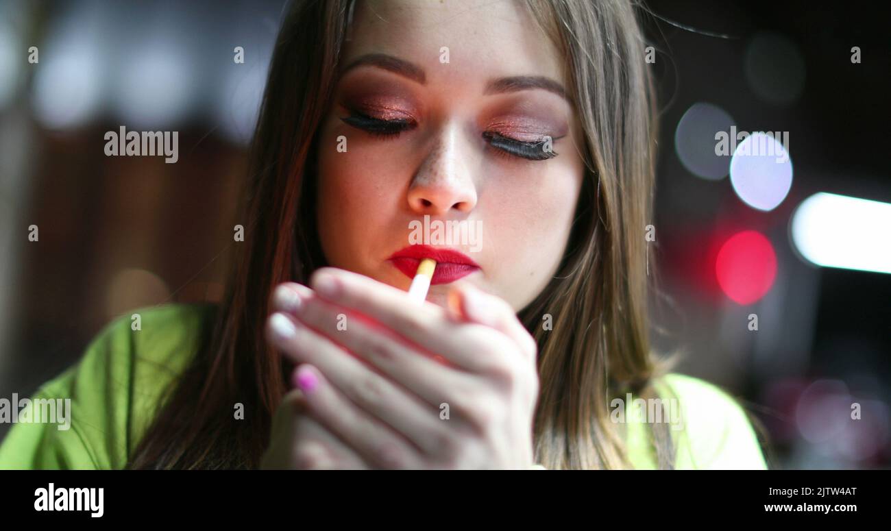 Pretty girl lighting a cigarette at night in nightlife Stock Photo - Alamy