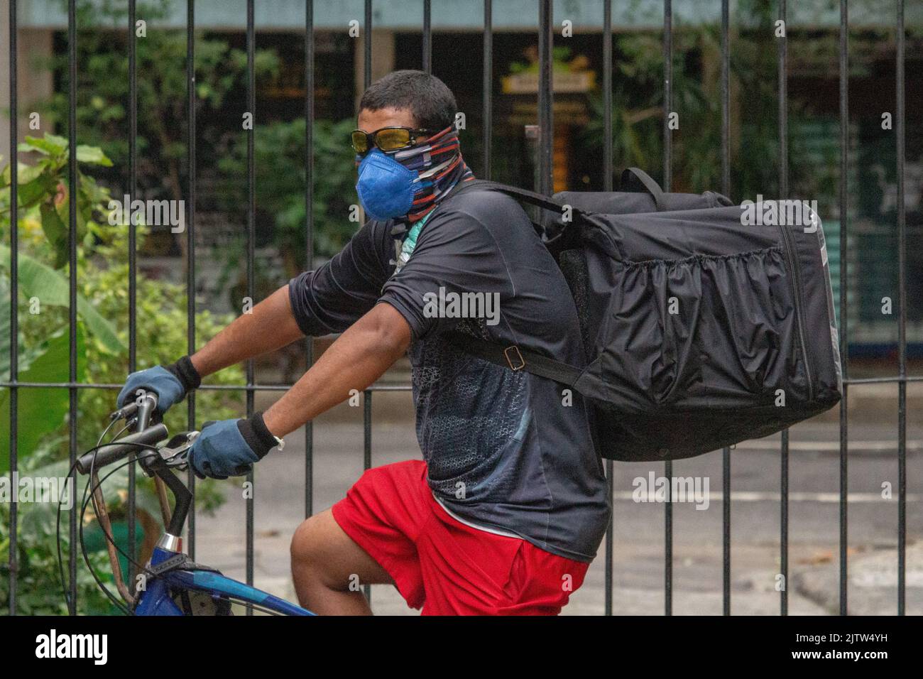 black man delivering food by bicycle on a street in Rio de Janeiro ...