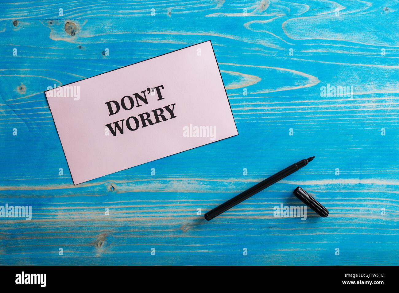 Light pink paper with Dont worry sign on it placed over textured blue ...