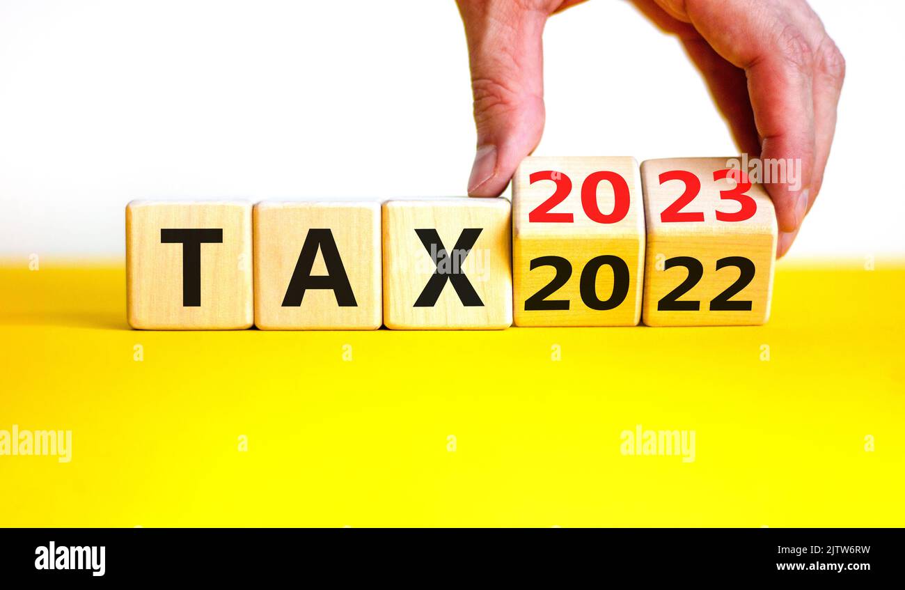 2023 tax new year symbol. Businessman turns a wooden cube and changes ...