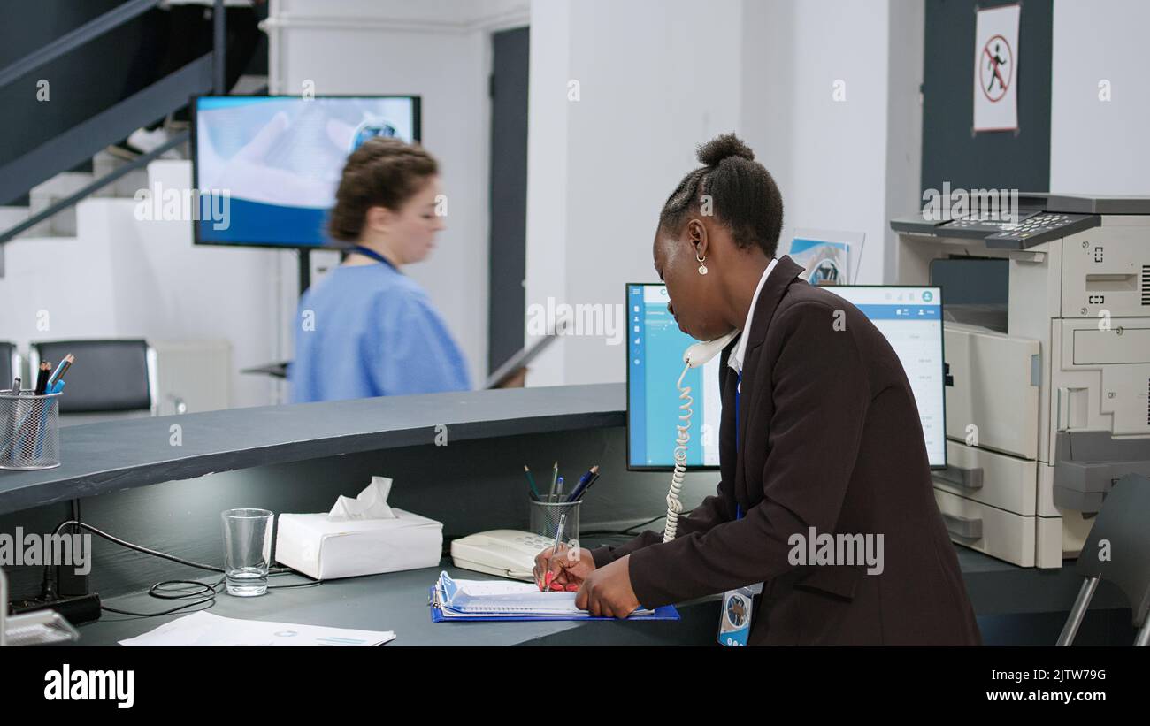 African american receptionist answering landline phone call to make ...