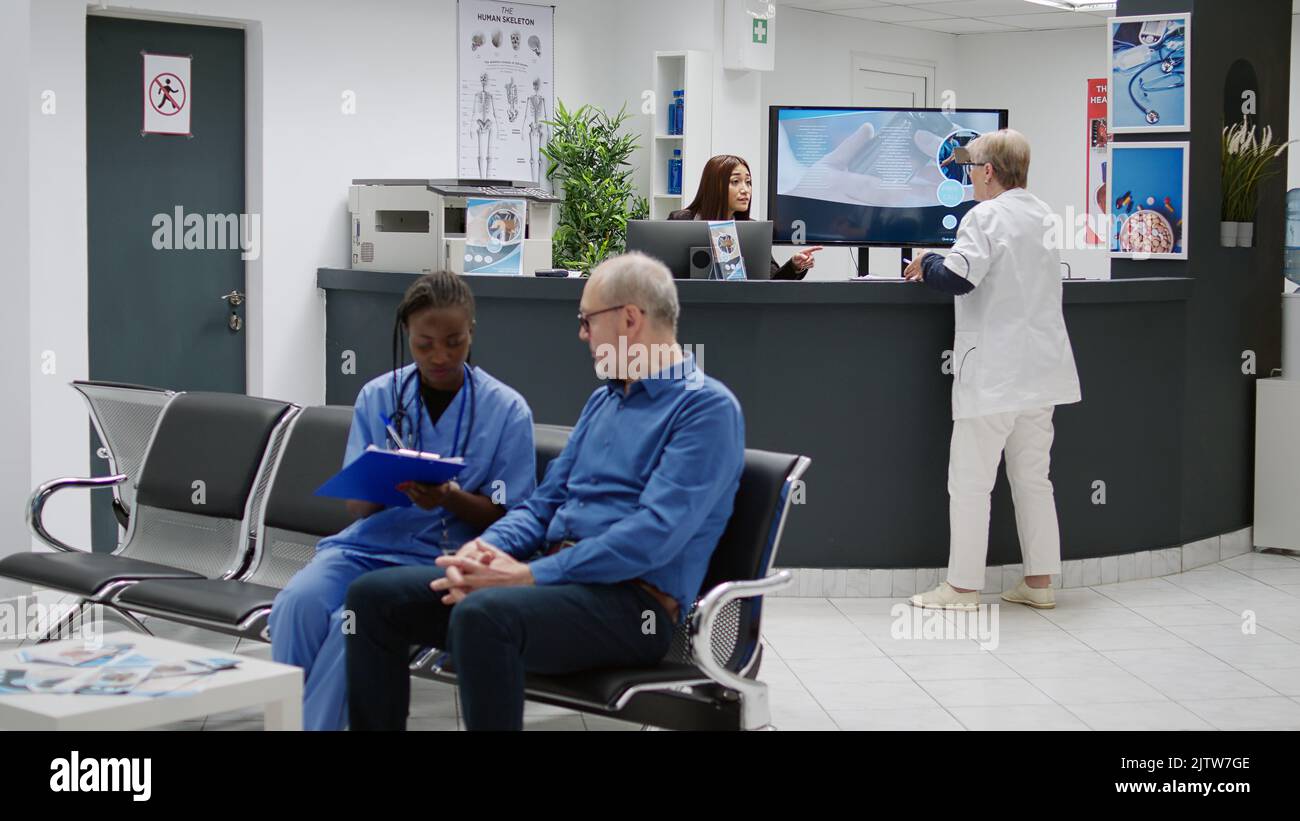Asian receptionist working at hospital reception counter, helping ...