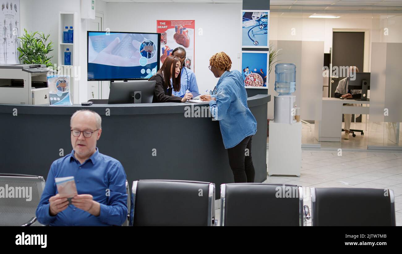 African american patient filling in checkup report at reception counter ...