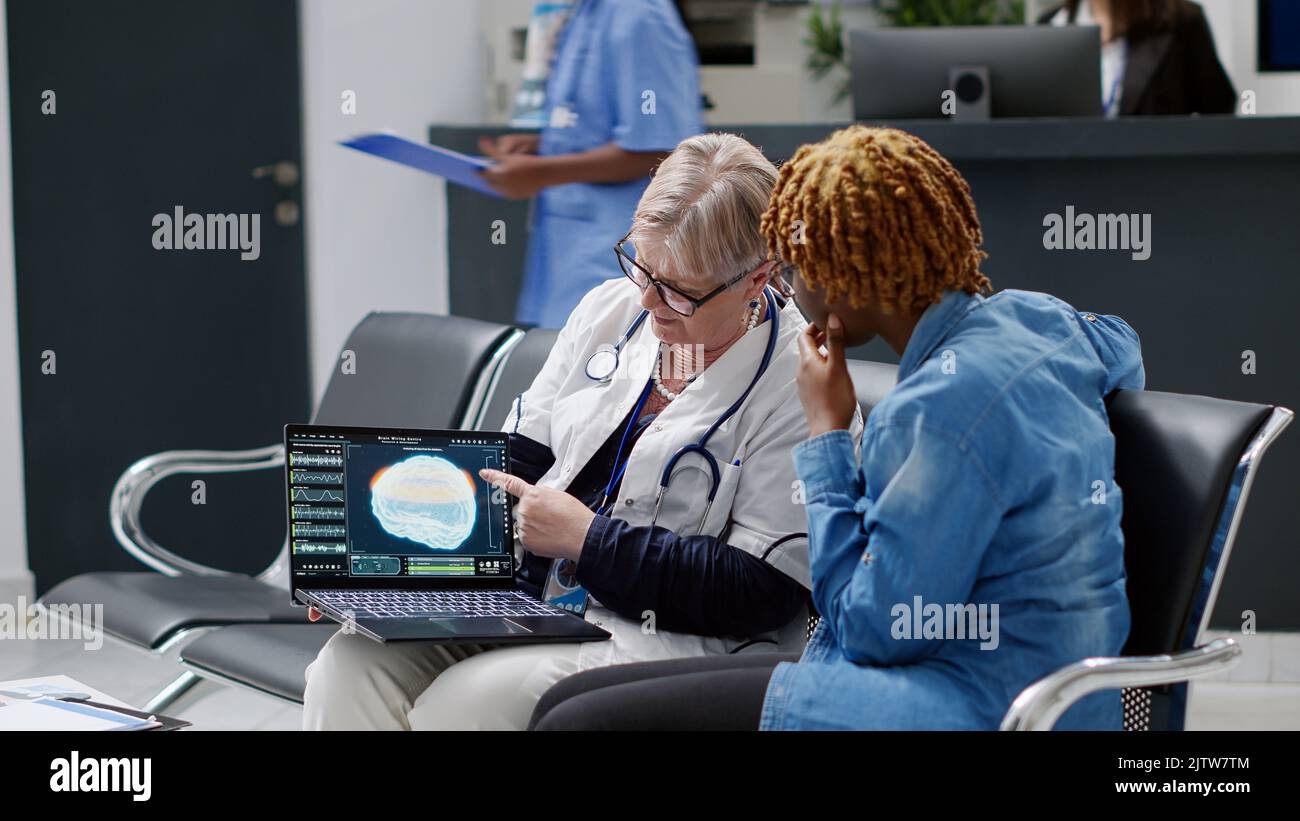Doctor and patient analyzing human brain scan on laptop, looking at ...