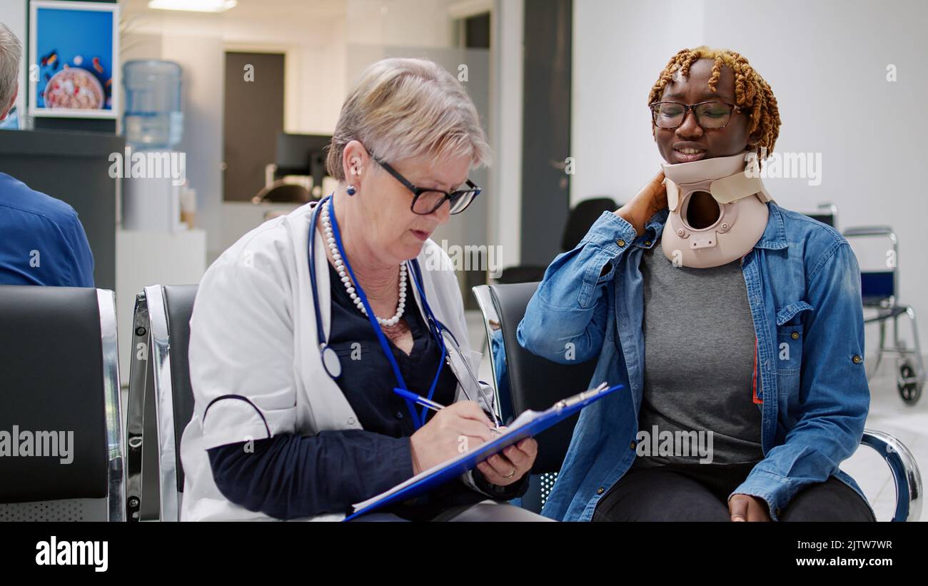 Old medic consulting african american woman with cervical collar ...