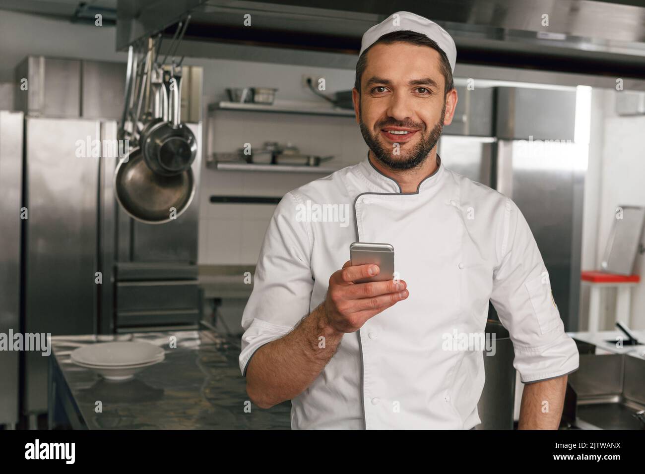 Chef cook using smart phone at the restaurant kitchen and looking ...