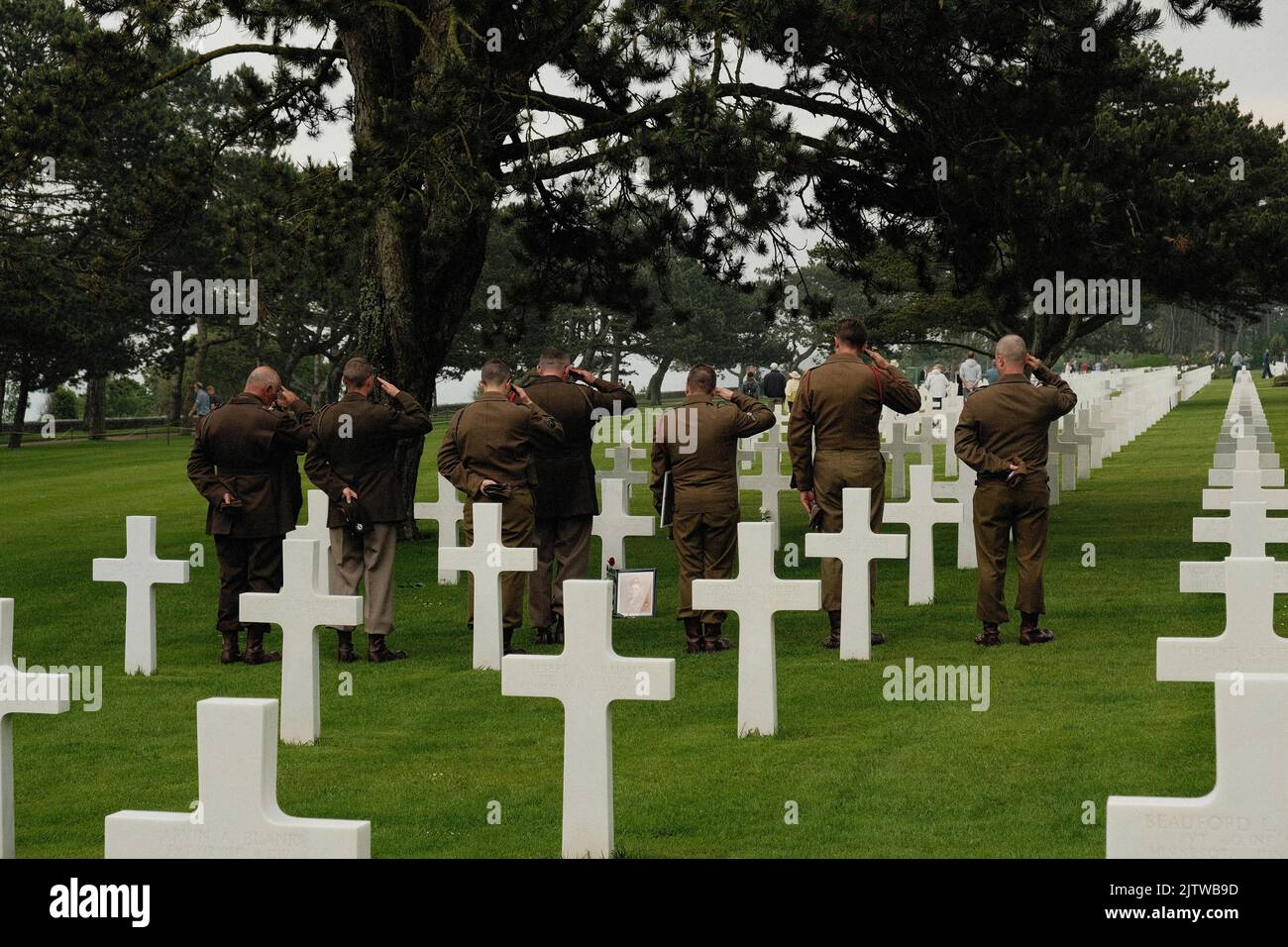 A touching view of men in uniform saluting in the Normandy American ...