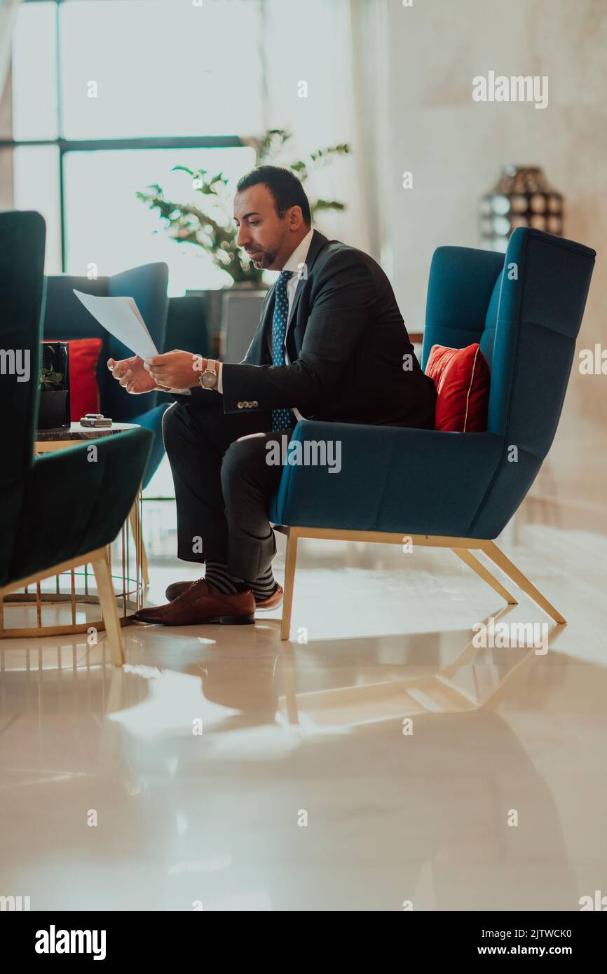A modern businessman in a suit sits in a modern office and examines ...