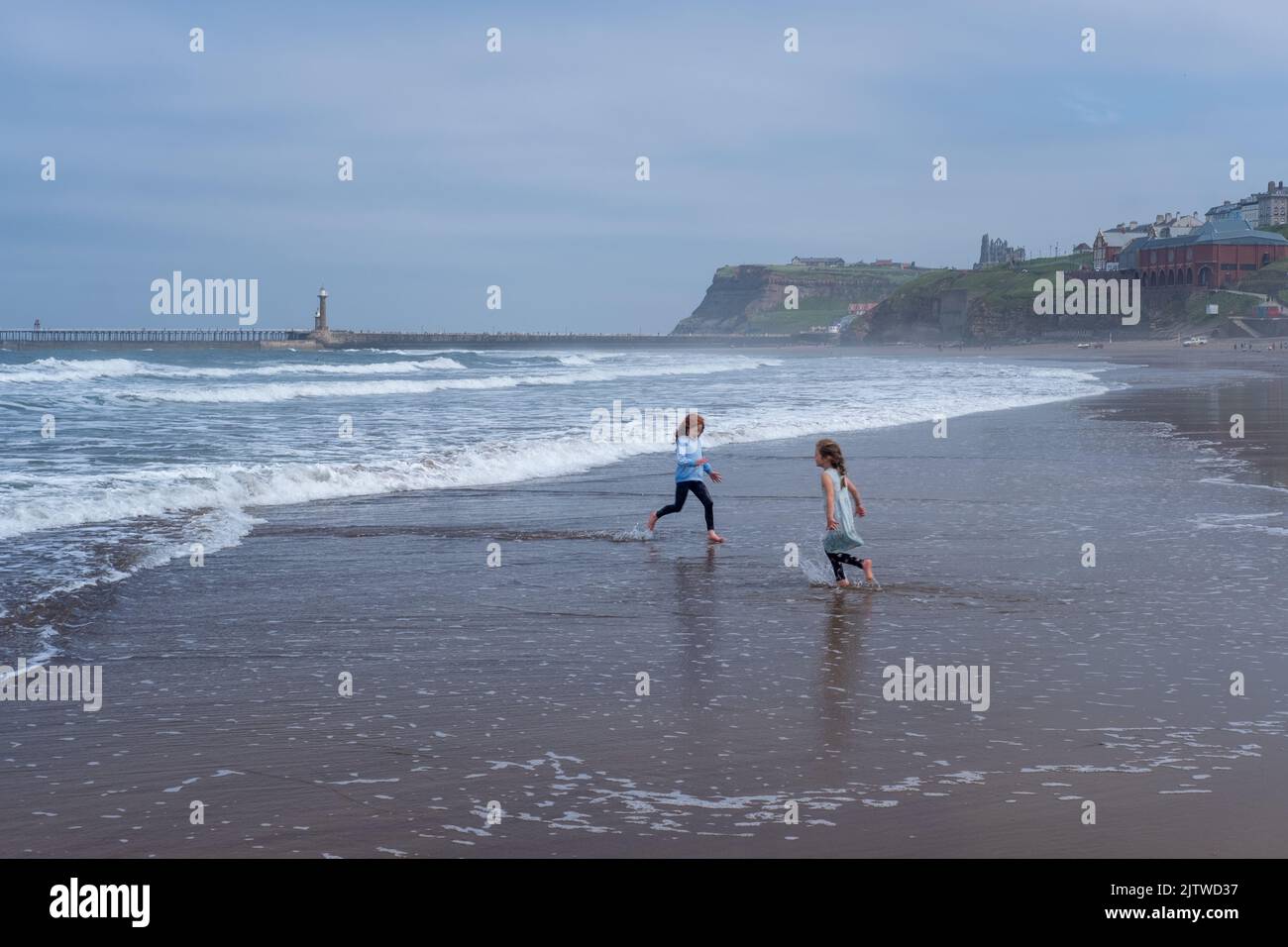 Two Children Playing on Whitby Beach with the Pier, Lighthouses ...