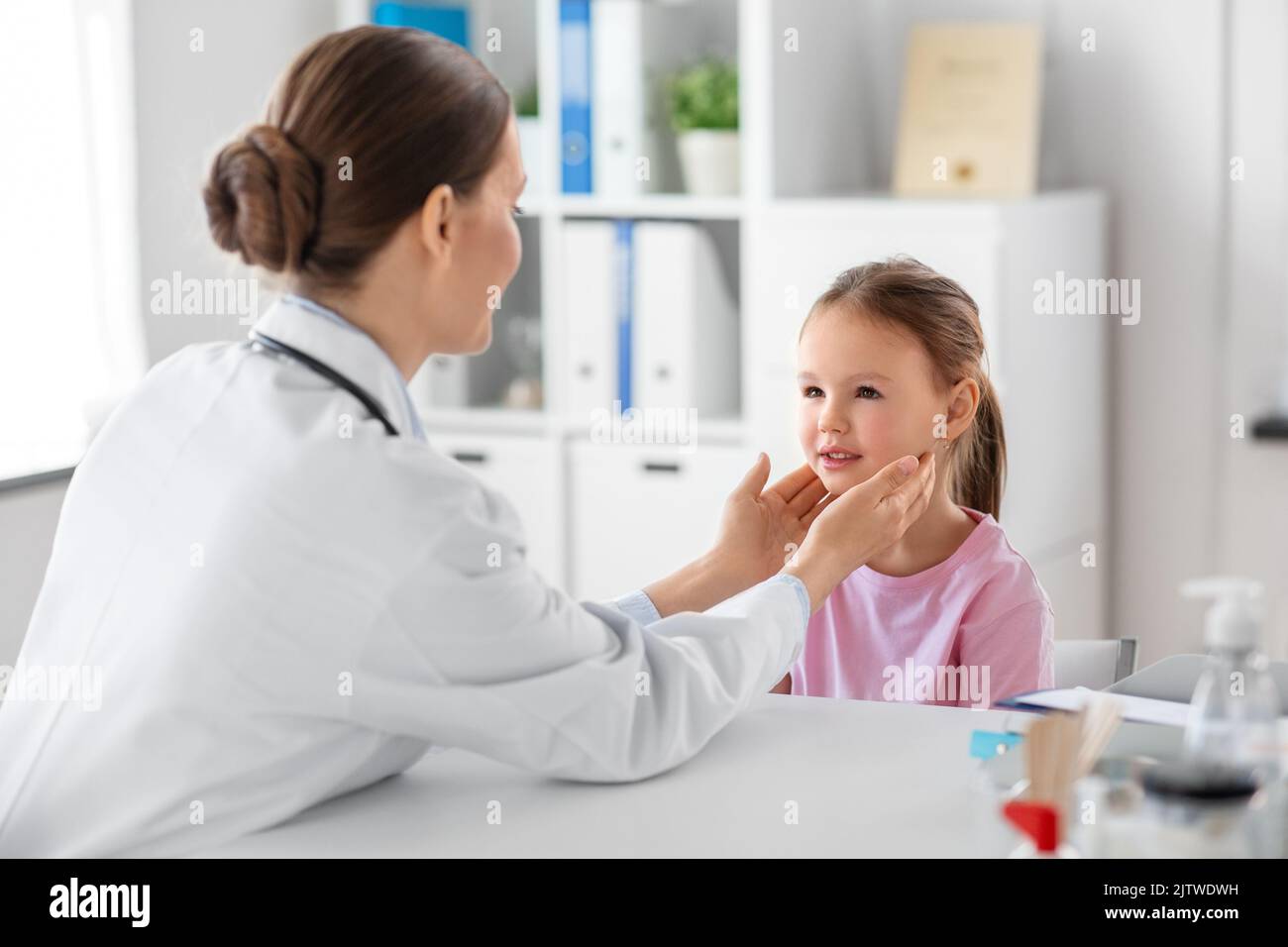 doctor checking girl patient's tonsils at clinic Stock Photo - Alamy