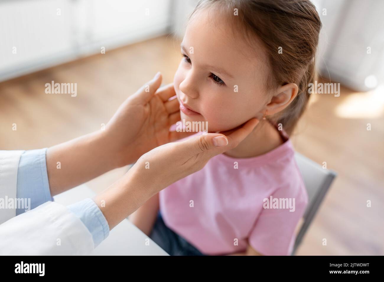 doctor checking girl patient's tonsils at clinic Stock Photo - Alamy
