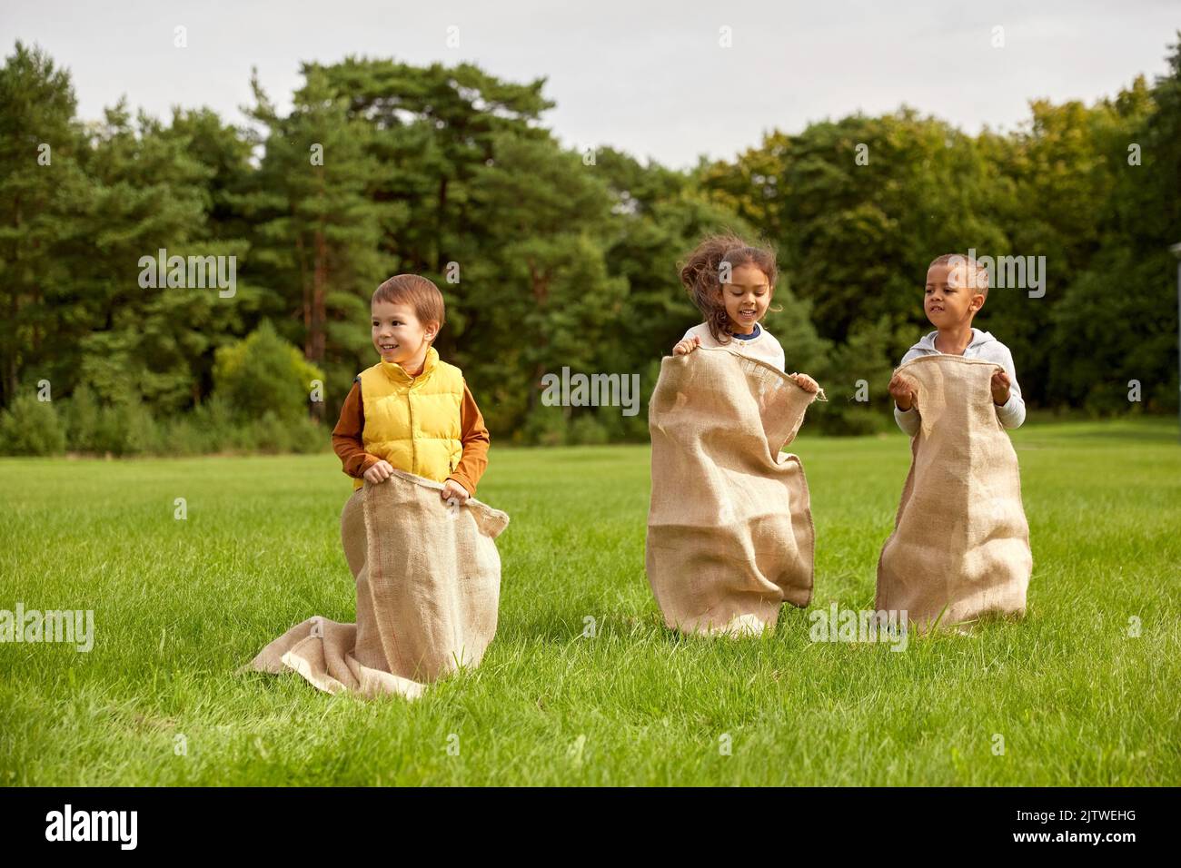 happy children playing bag jumping game at park Stock Photo - Alamy