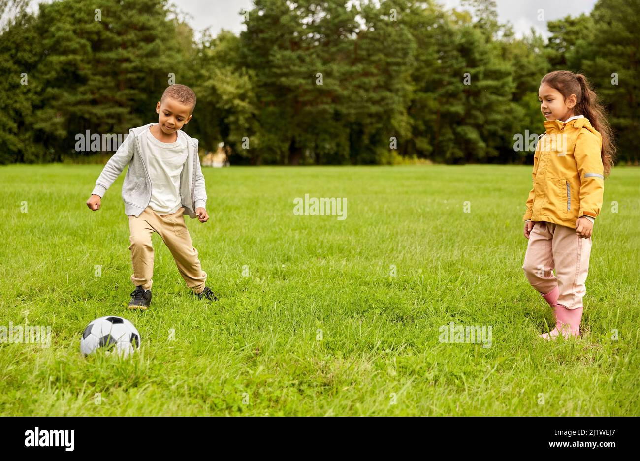 little children with ball playing soccer at park Stock Photo - Alamy