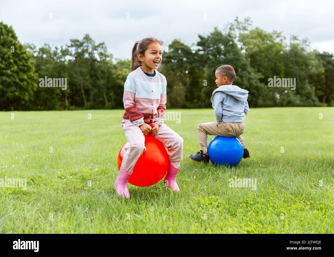 happy children bouncing on hopper balls at park Stock Photo - Alamy