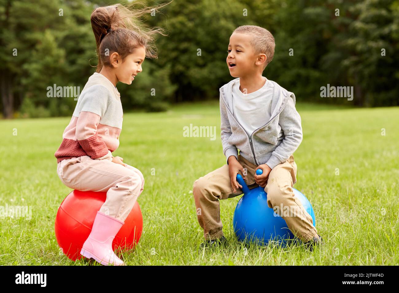 happy children bouncing on hopper balls at park Stock Photo - Alamy