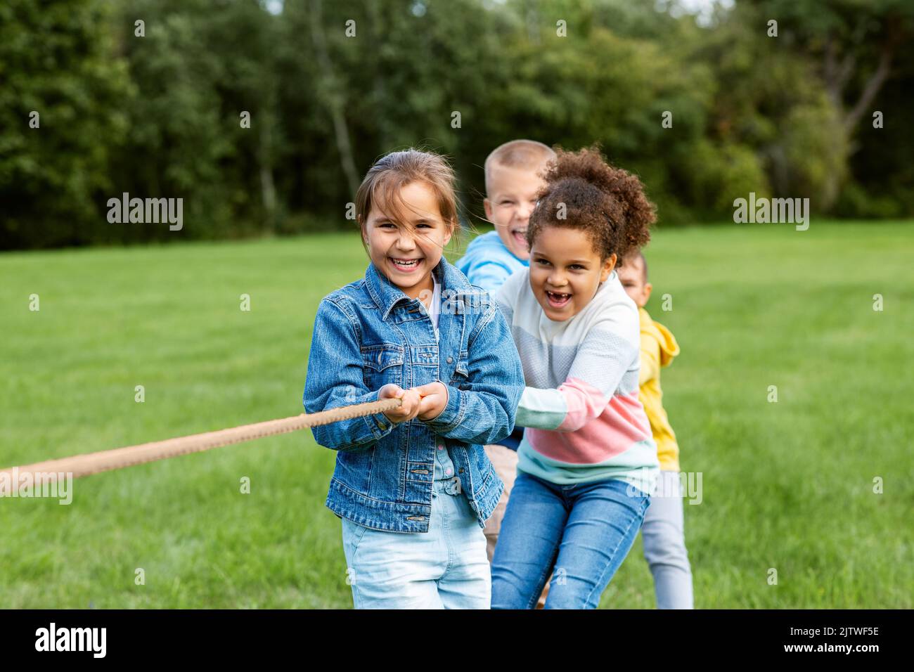 happy children playing tug-of-war game at park Stock Photo - Alamy