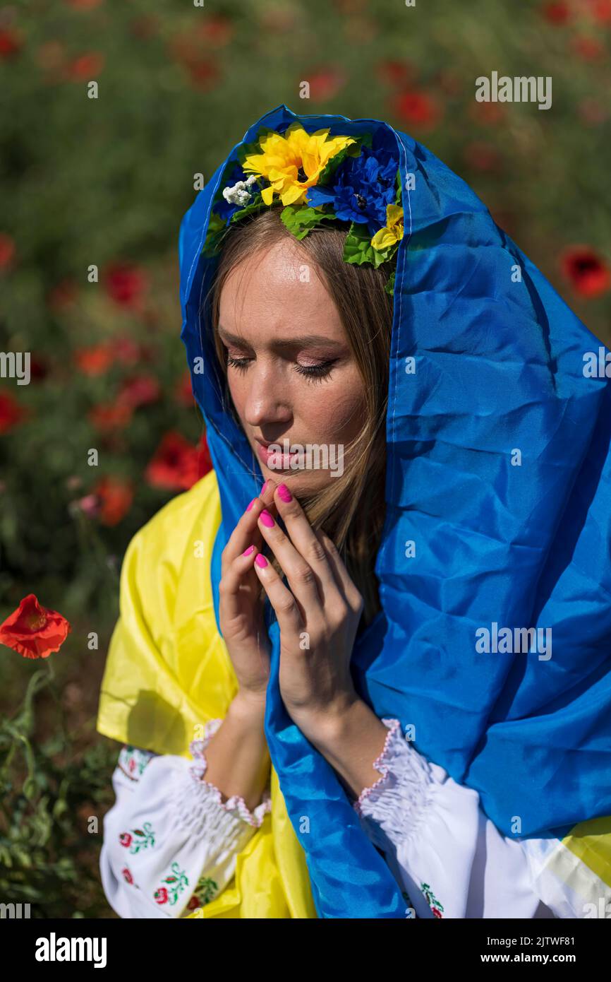 A young blonde Ukrainian woman stands in a field of Red Poppy flowers ...
