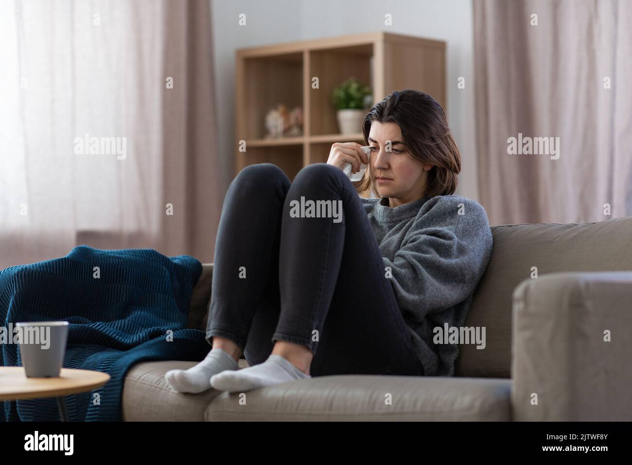 sad crying woman sitting on sofa at home Stock Photo - Alamy